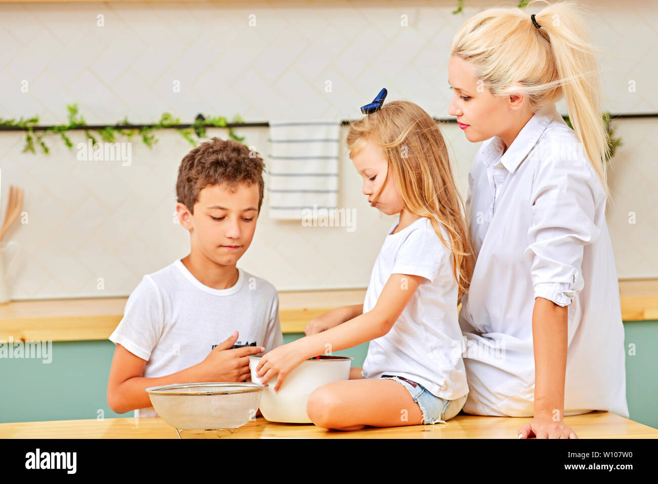 Mom is baking cookies with her kids at home kitchen Stock Photo - Alamy