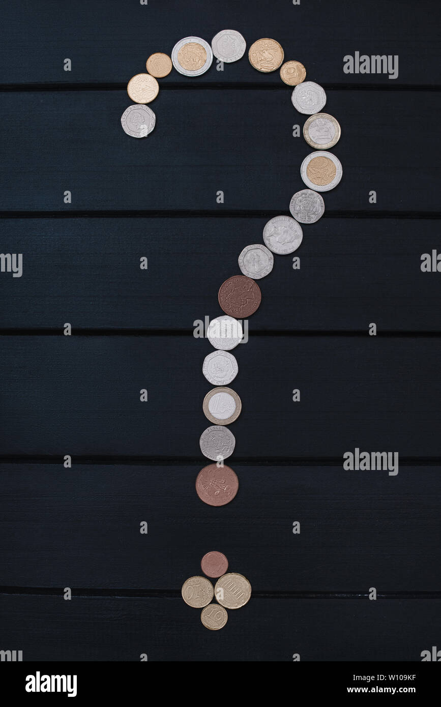 Scattered coins of different countries in the form of a question mark ...