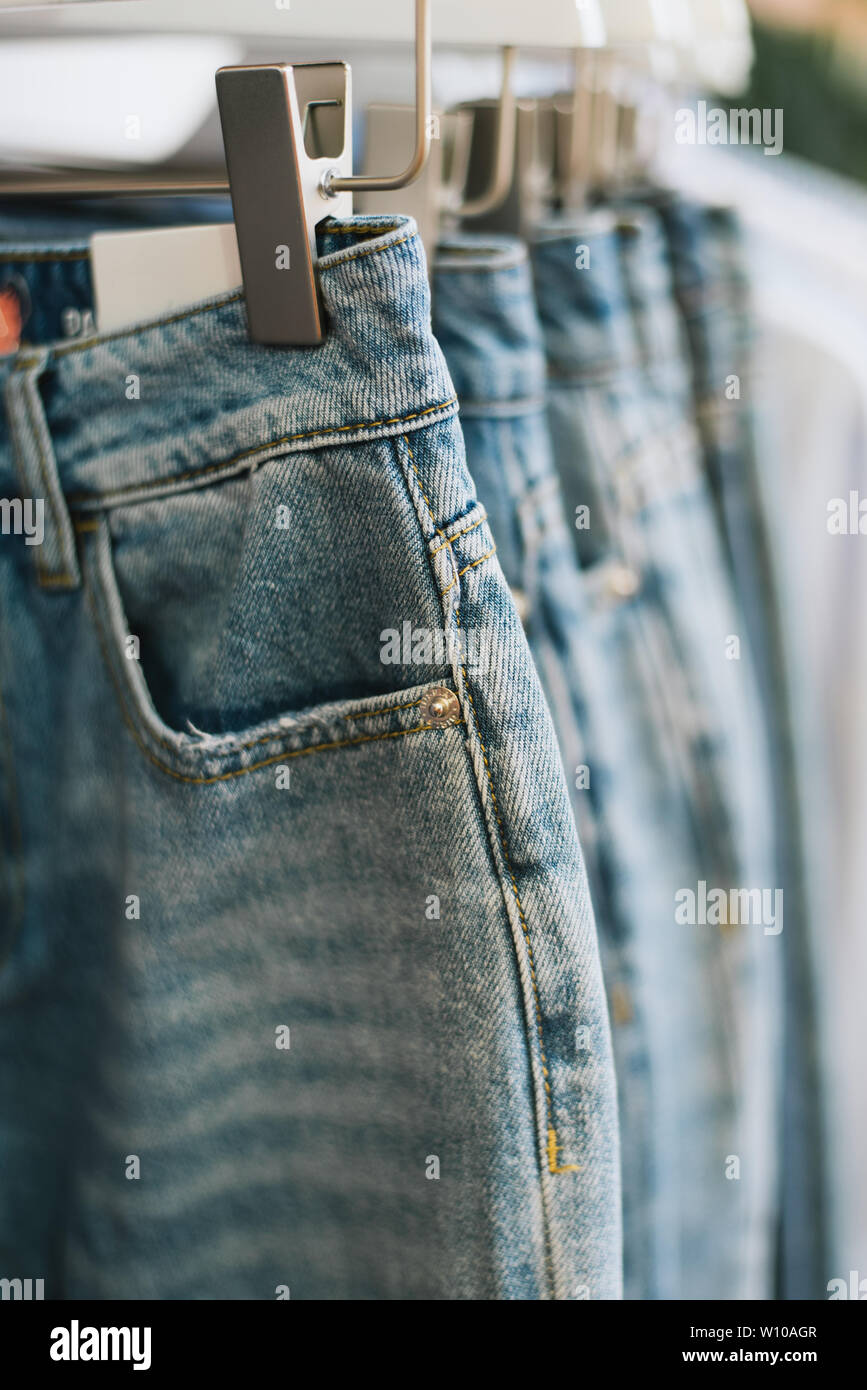 Jeans hang on hangers in the store. Vertical photo Stock Photo - Alamy