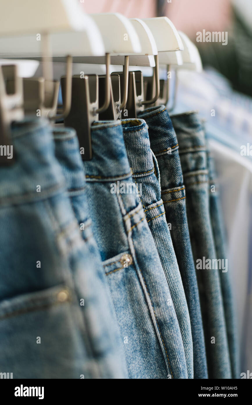 Jeans hang on hangers in the store. Vertical photo Stock Photo - Alamy