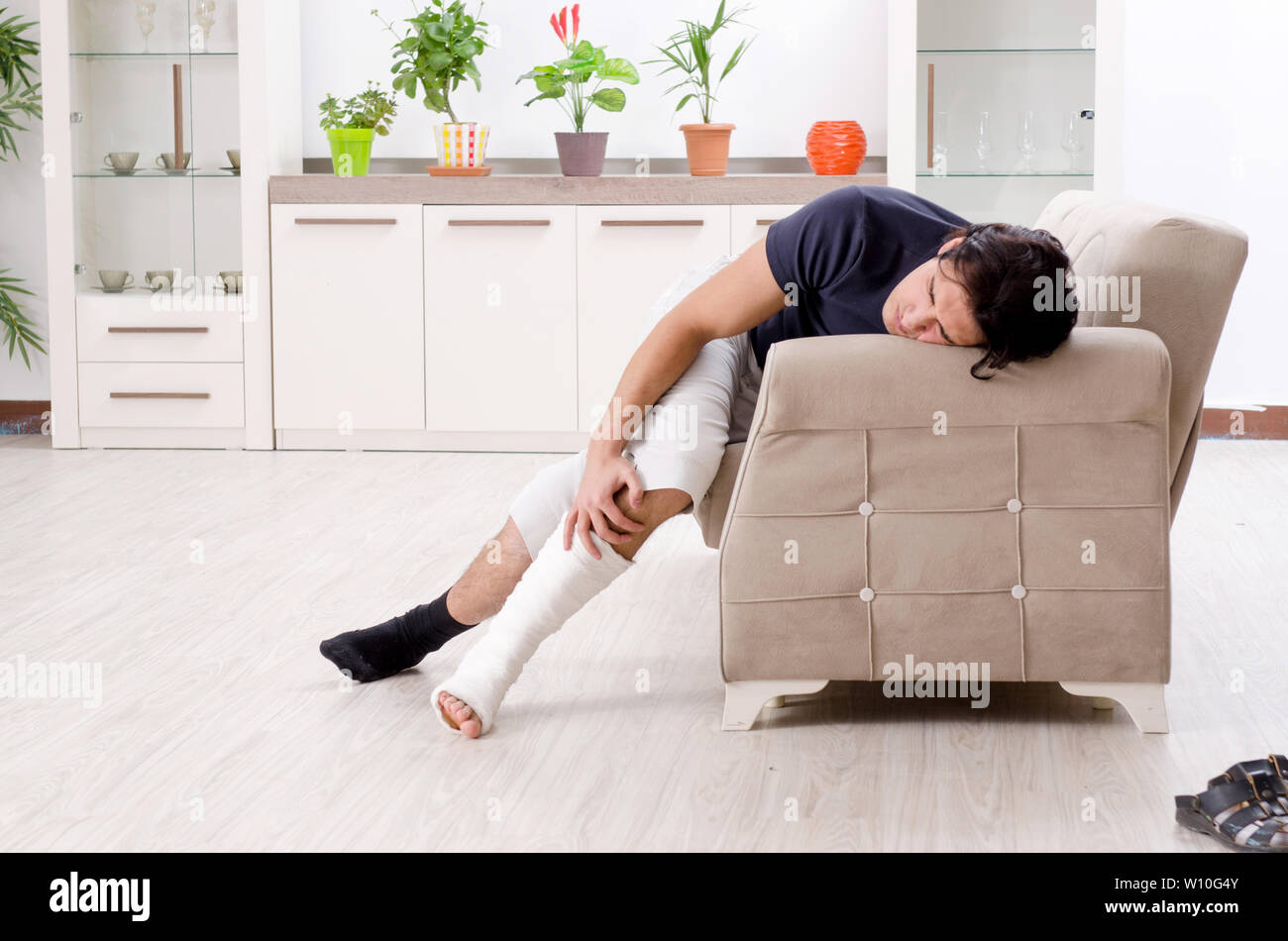 Leg injured young man suffering at home Stock Photo - Alamy