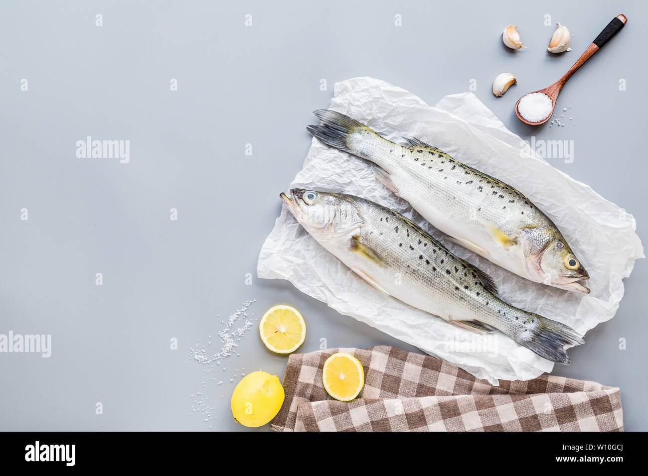 Fresh raw fish with spices, lemon, salt on gray background. Creative ...