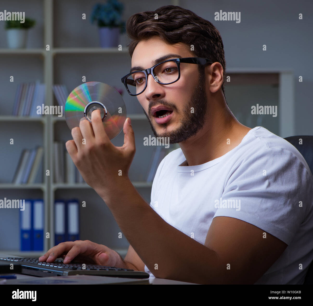 Young man staying late in office to do overtime work Stock Photo - Alamy