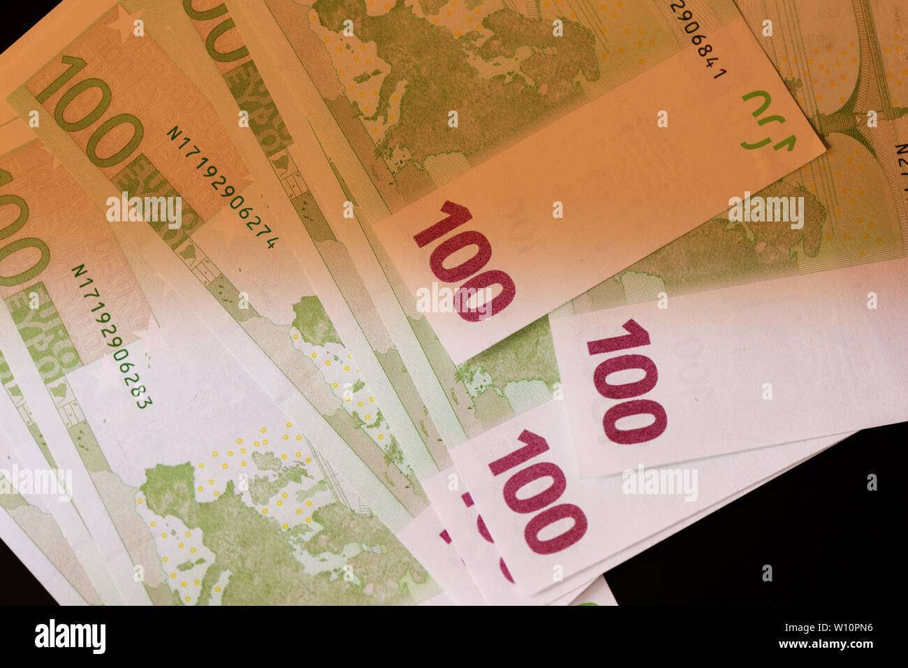 One hundred euro notes on a dark background close up. Brown color toned ...