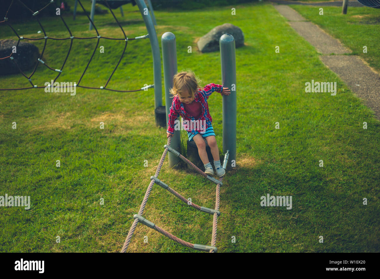 A little toddler is walking on a rope at the playground Stock Photo - Alamy