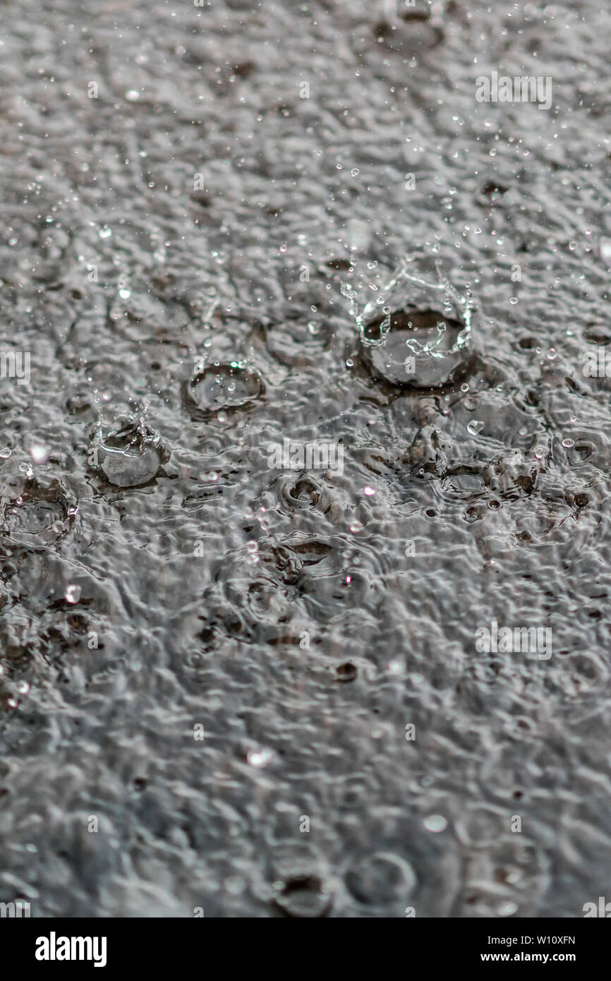 rain gray background. Drops on a puddle. Vertical photo Stock Photo - Alamy