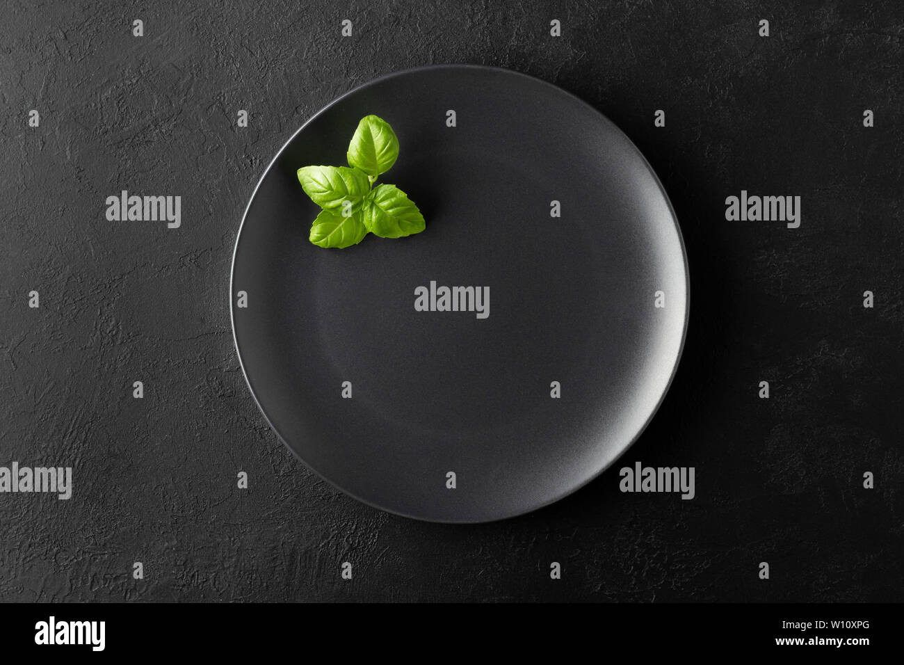 Table setting. Black plate and basil leaves over dark background Stock ...