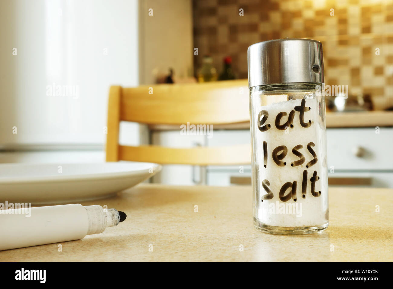 Eat less salt handwritten on glass container Stock Photo - Alamy