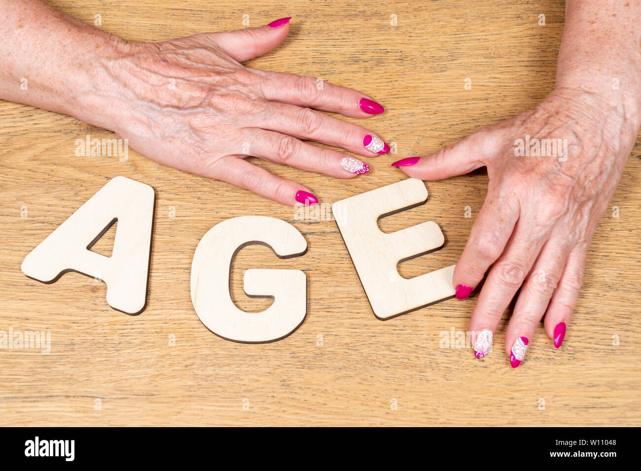 word age, spread out of wooden letters with old female hands with a ...