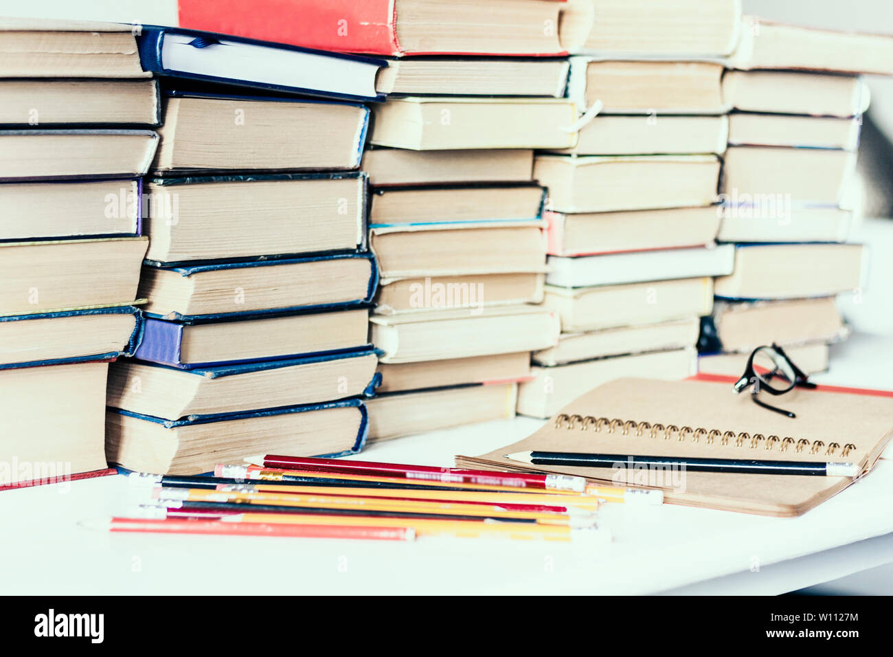Stack of old books, textbook, notebook, glasses and pencils on white ...