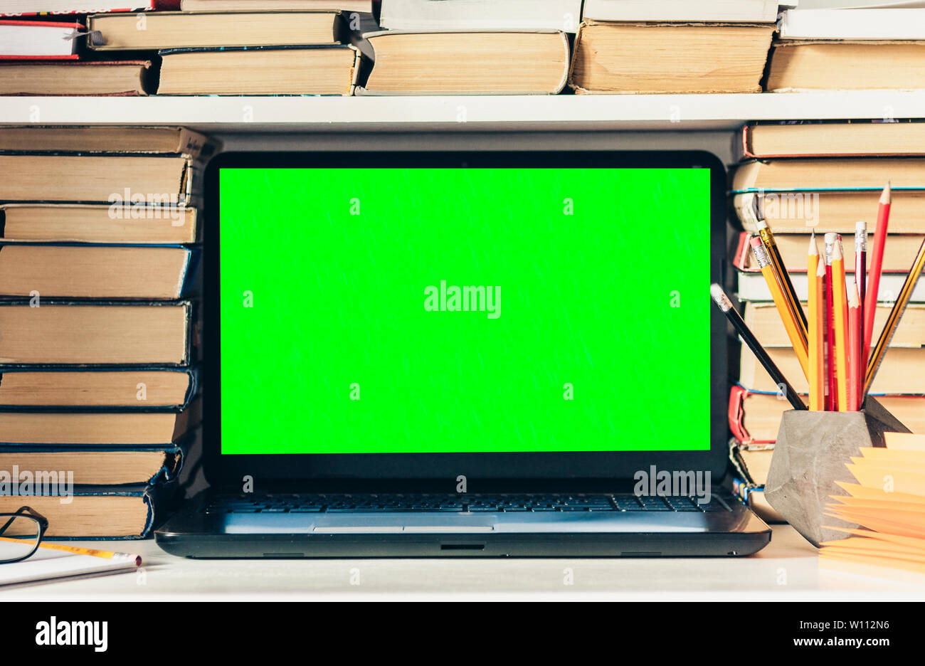 Green screen laptop, stack of books, notebook and pencils on white ...