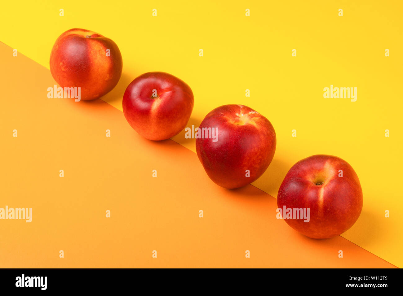 four nectarines on orange yellow background Stock Photo - Alamy