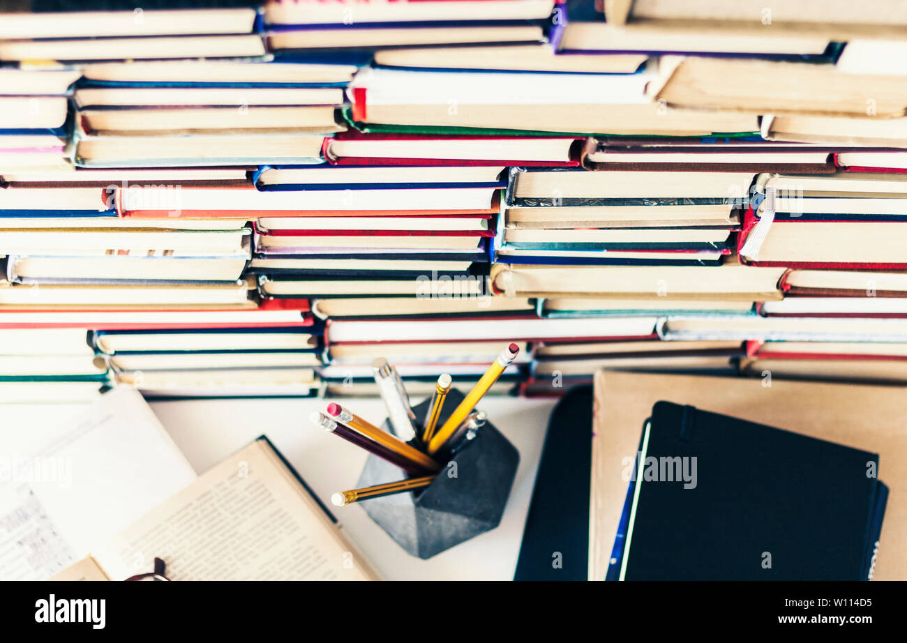Laptop, stack of books, notebook, pencils in office background for ...