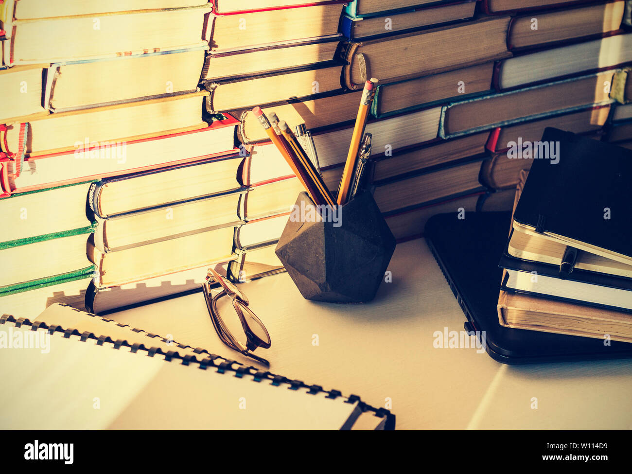 Laptop, stack of books, notebook, pencils in office background for ...