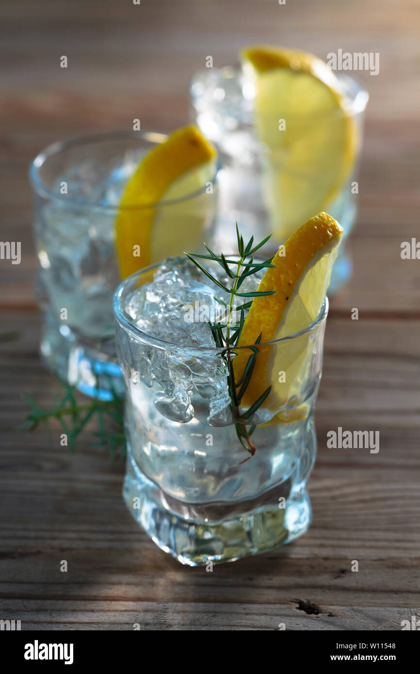 Gin with lemon, juniper and ice on a old wooden table Stock Photo - Alamy