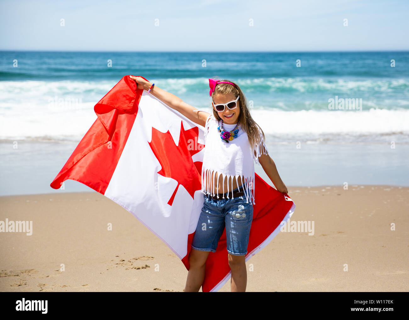 Happy Canadian girl carries fluttering white red flag of Canada against ...