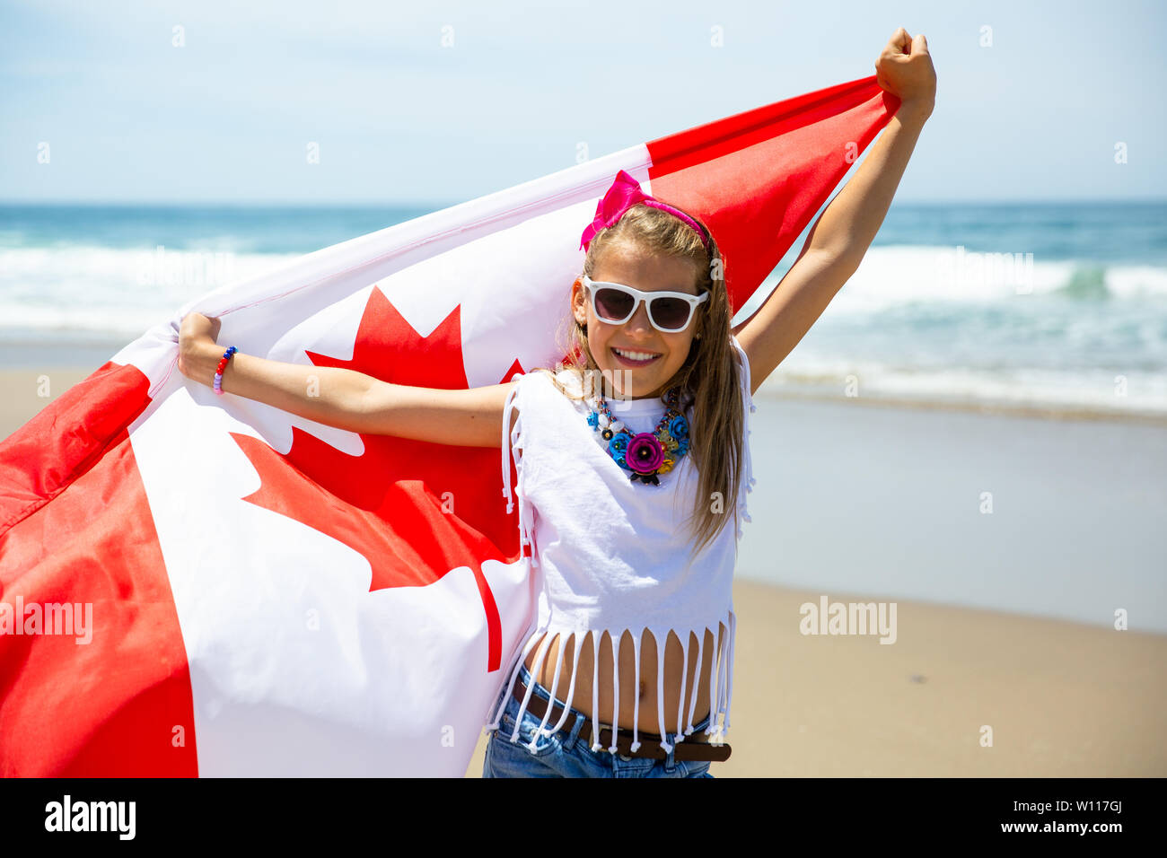 Happy Canadian girl carries fluttering white red flag of Canada against ...