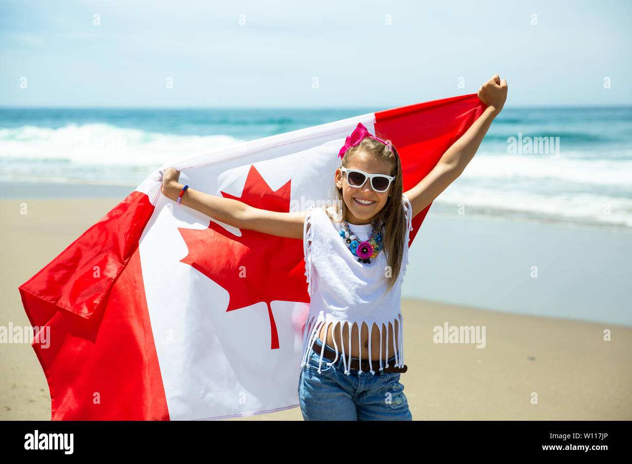 Happy Canadian girl carries fluttering white red flag of Canada against ...