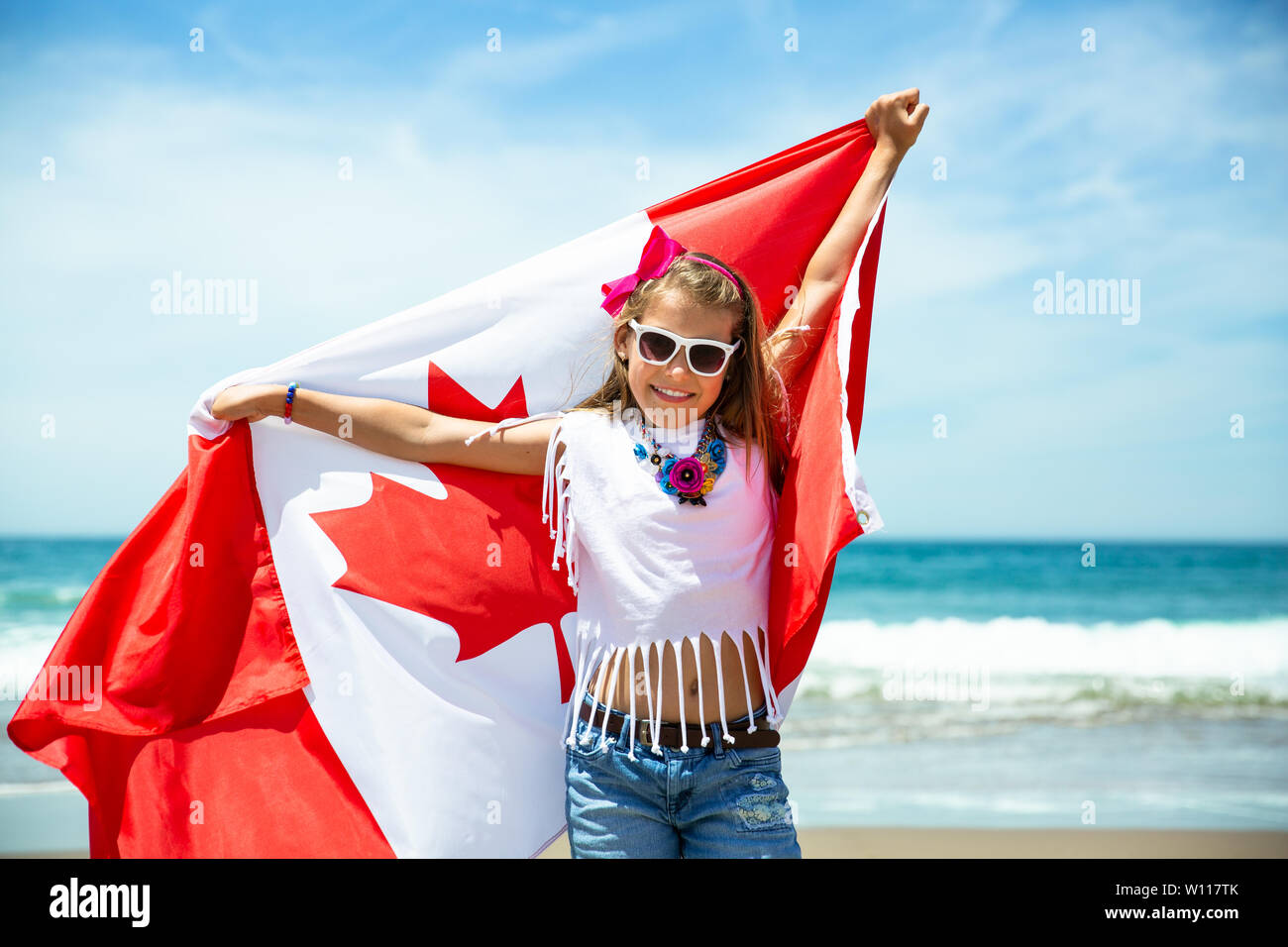 Happy Canadian girl carries fluttering white red flag of Canada against ...