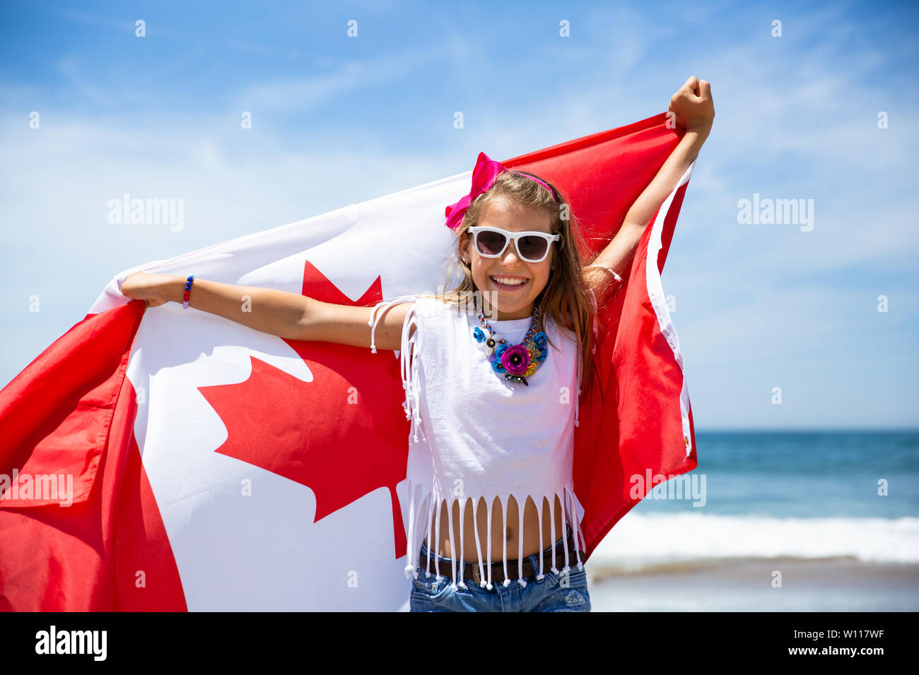 Happy Canadian girl carries fluttering white red flag of Canada against ...