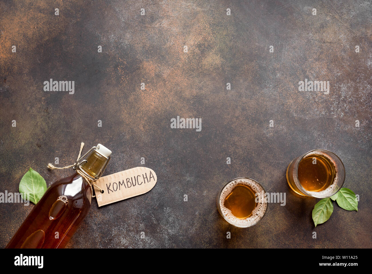Kombucha fermented drink in glass and bottle on dark background, copy ...