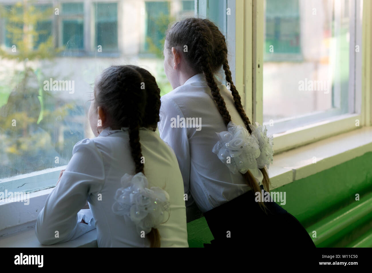 Schoolgirls teenagers stand near the window in the school hallway Stock ...