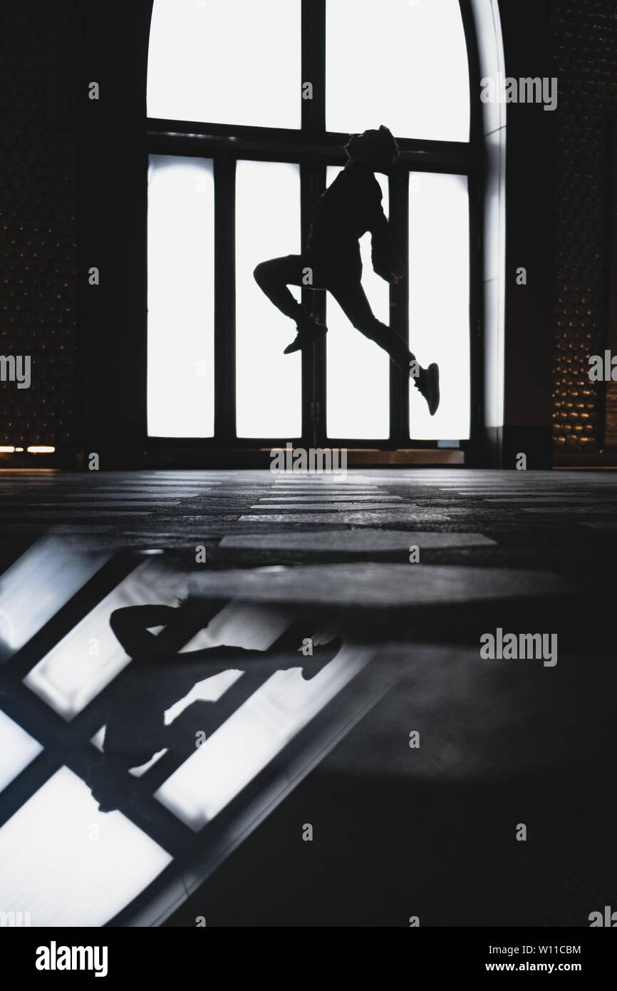 Silhouette of a male ballet dancer in a dark area with his reflection ...