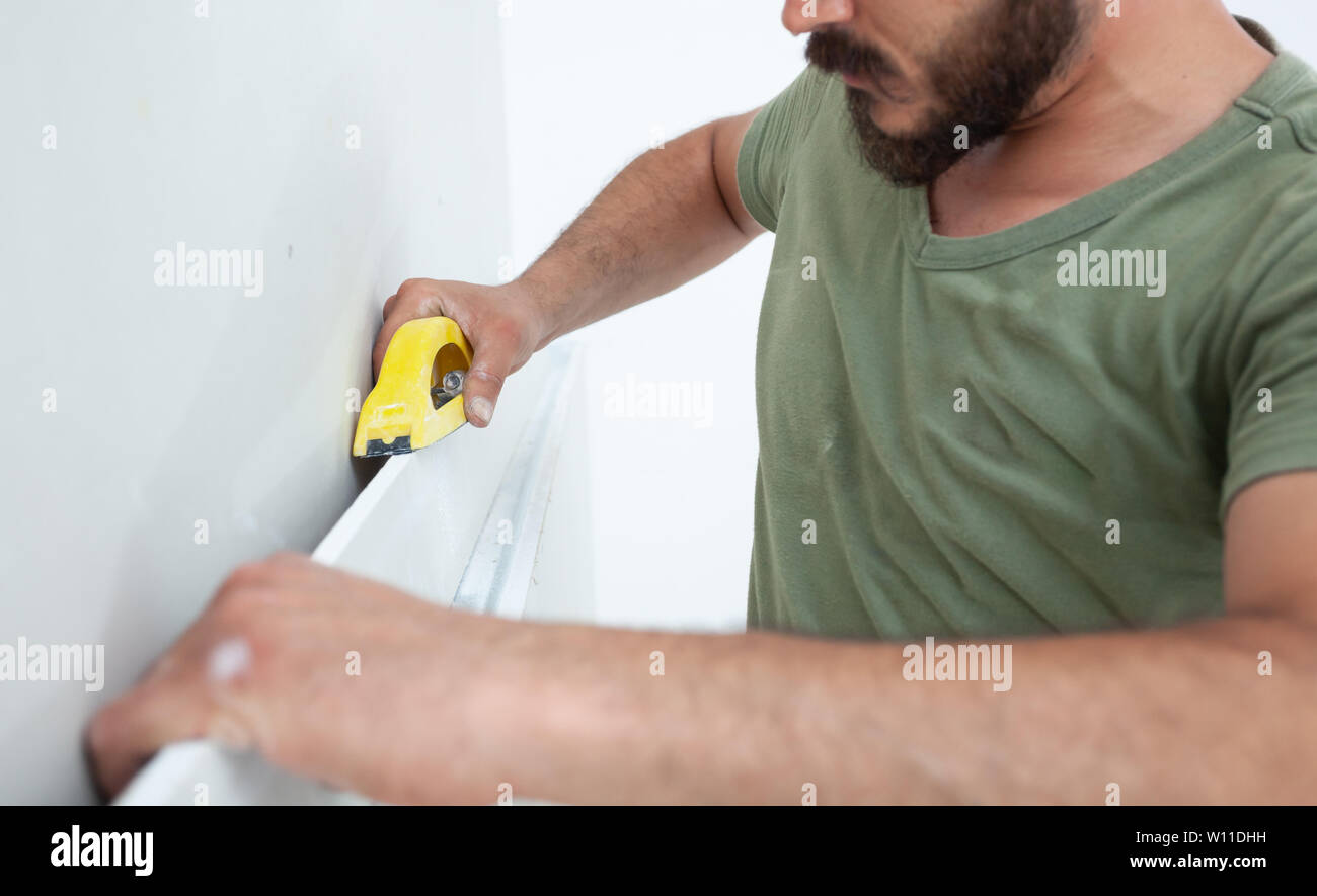 Worker building plasterboard wall. Working with cutting tools, fixing ...