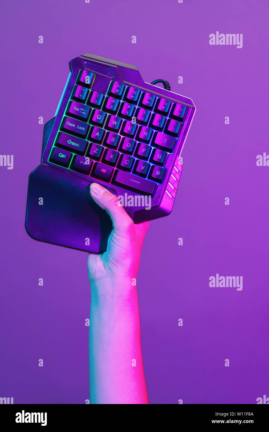 Hand with gamers keyboard on violet background. Gamer concept Stock ...