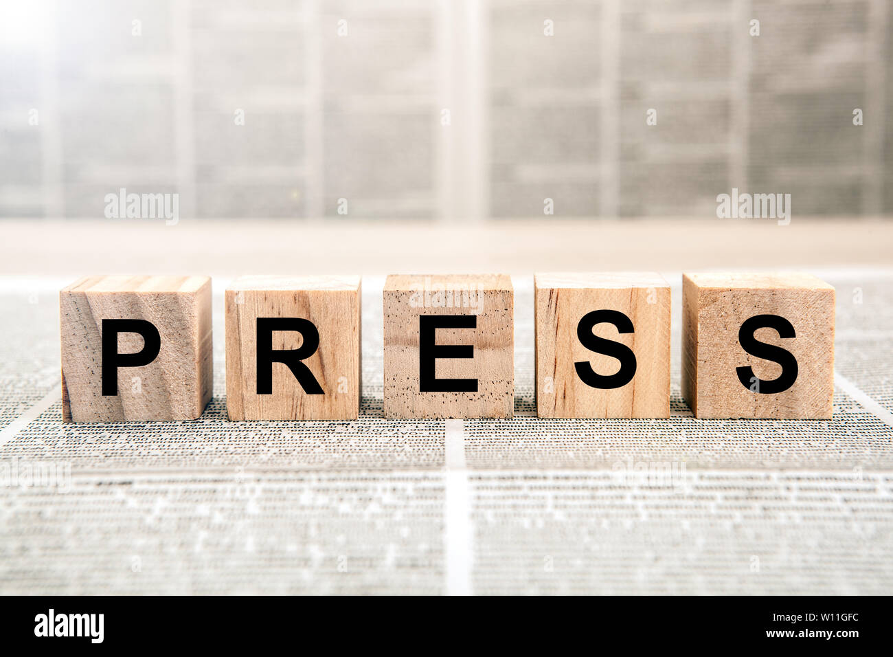 Five wooden cube blocks with the text press on a newspaper background ...