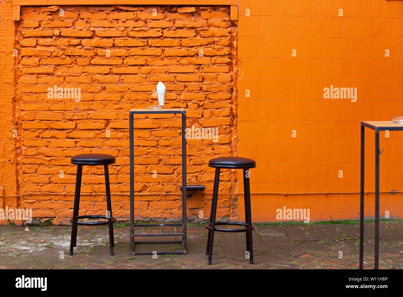 Black bar chairs and orange brick floor laid in fishbone style, covered ...