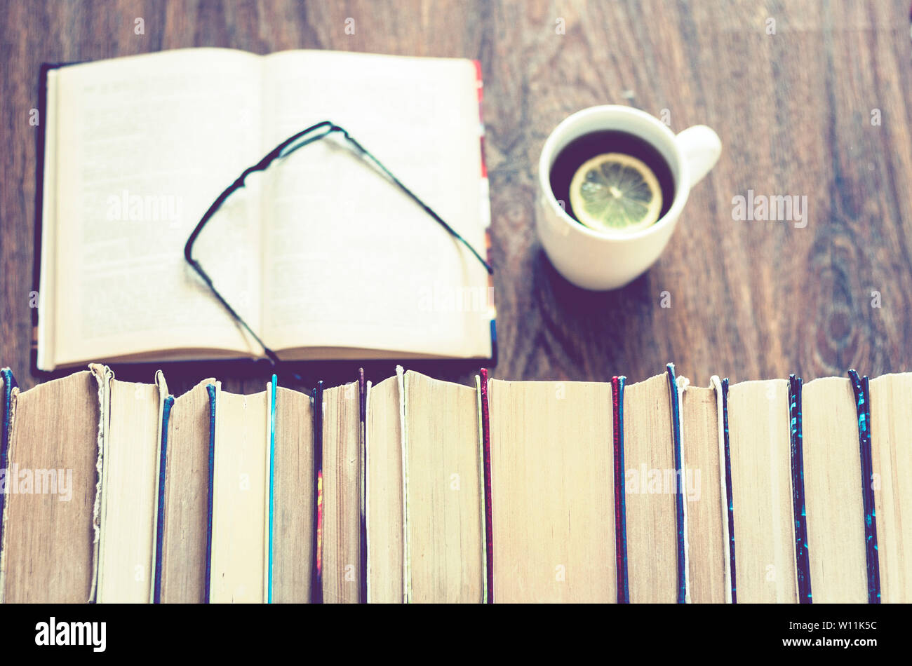 Stack of books education background, open book, glasses, and cup of tea ...