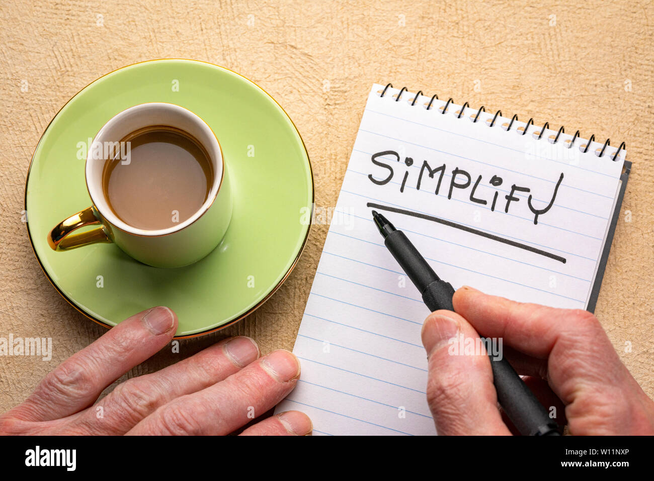 Simplify word - man hand writing a note with a black marker in a spiral ...