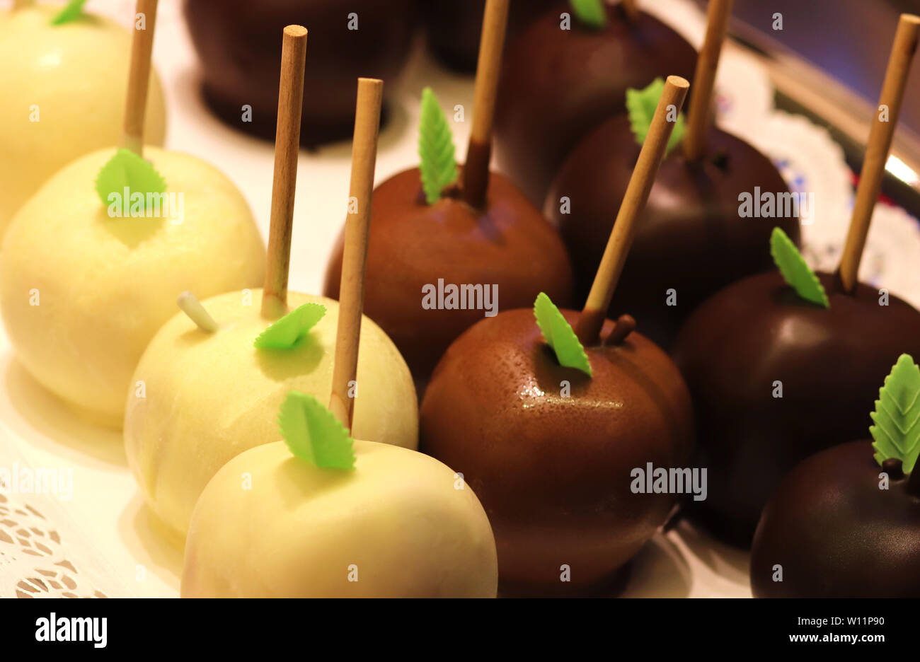 variety of chocolate apples on a stick, decorated with sugar leaves, at ...