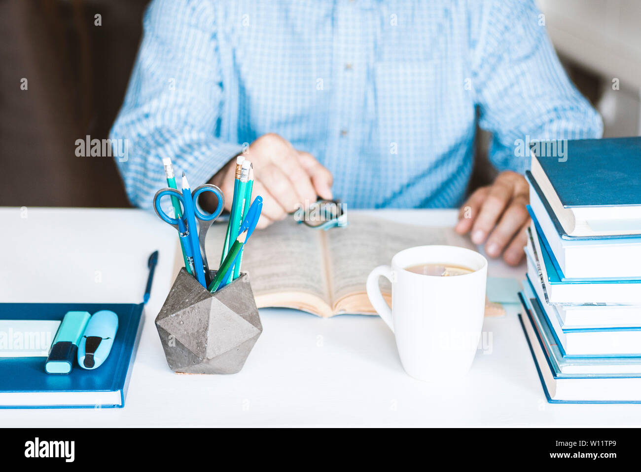 man in blue shirt reading book on modern stylish work place with office ...