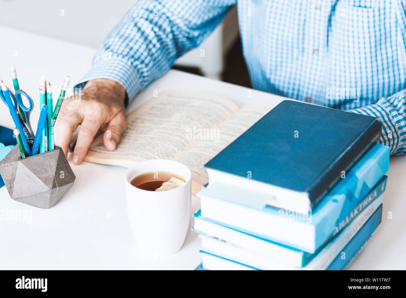man in blue shirt reading book on modern stylish work place with office ...