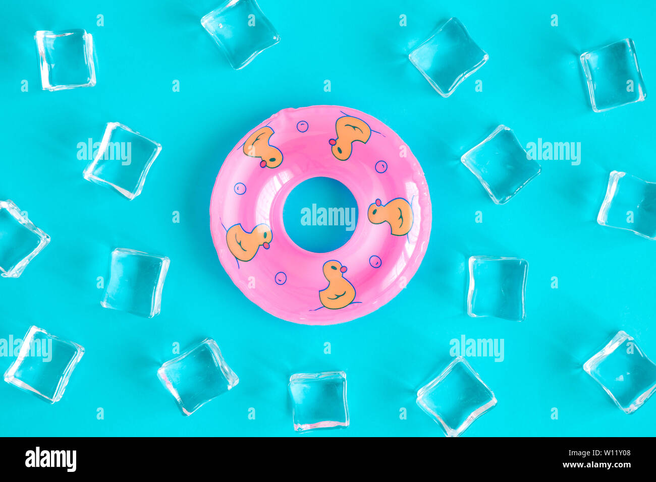 Flat lay of inflatable pool float and ice cubes isolated on blue ...