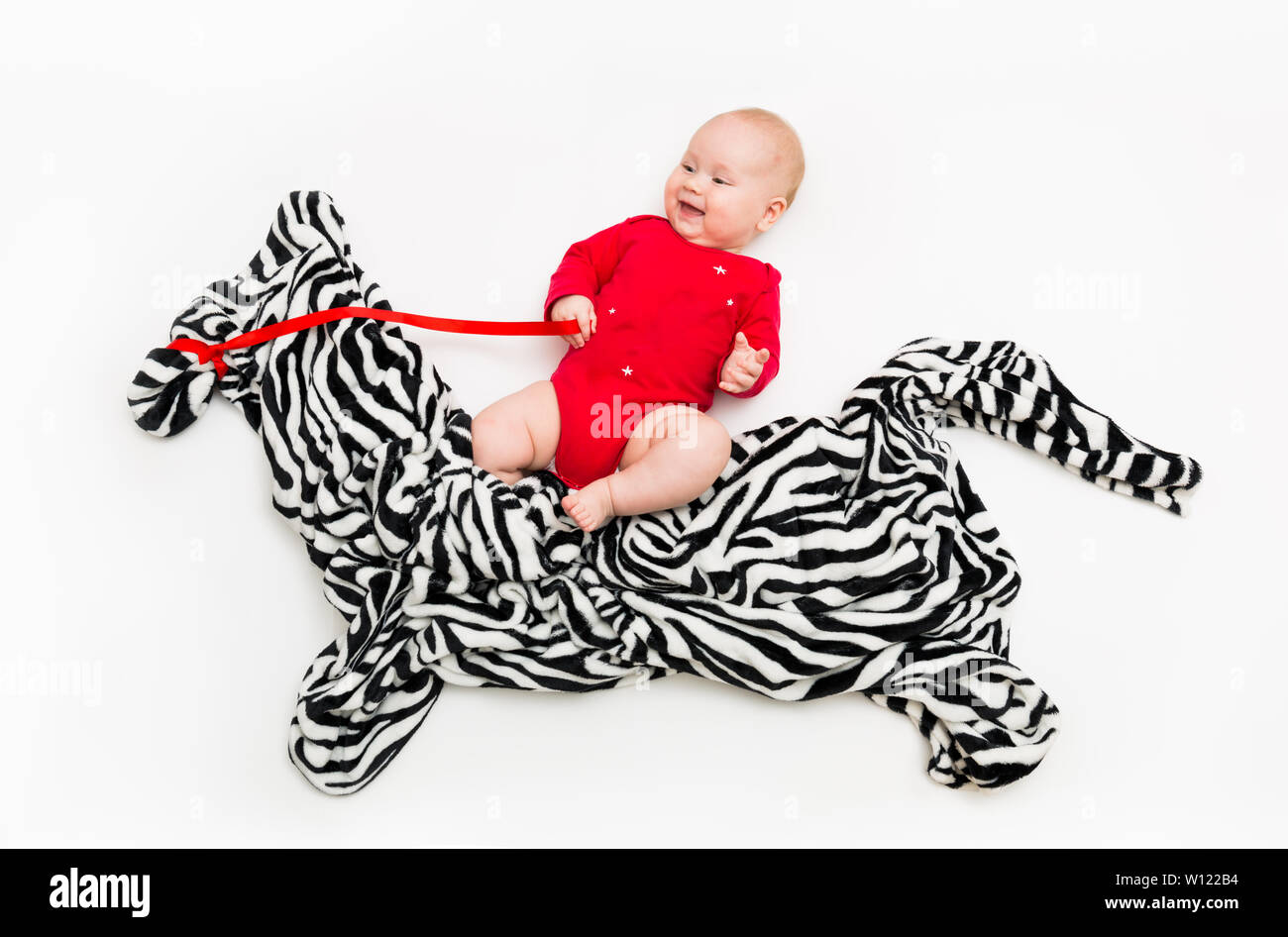 a four-month-old child rides a Zebra from a cloth on the floor Stock ...