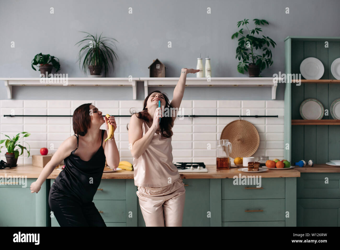Sisters listening to music and dancing during breakfast Stock Photo - Alamy