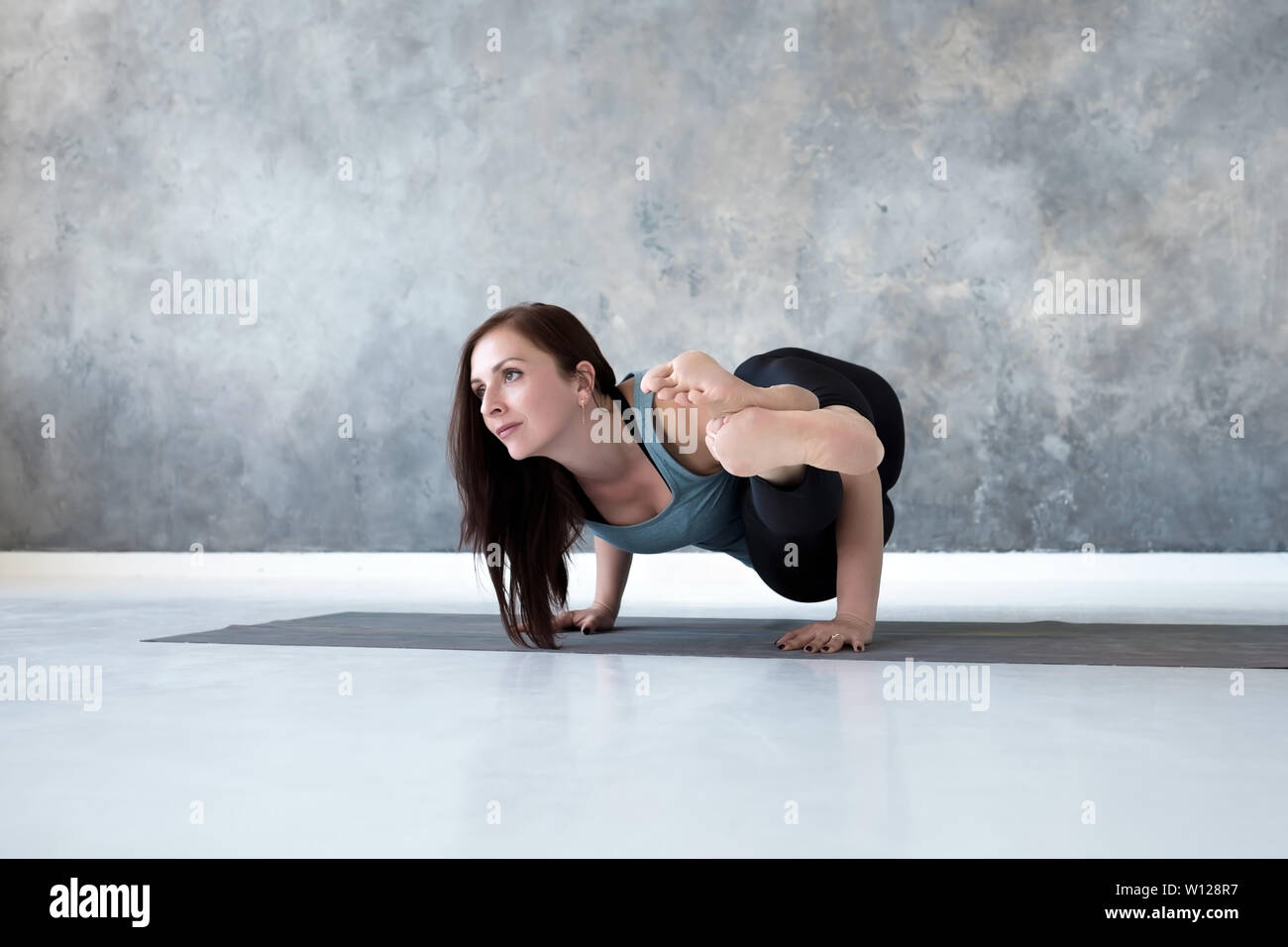 Young woman holding arm balance in Astavakrasana yoga pose Stock Photo ...