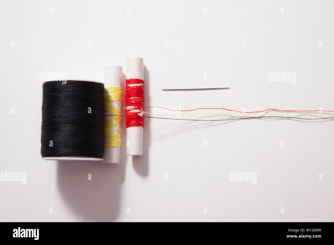 Various sizes and colours of thread and a needle spread long against a ...