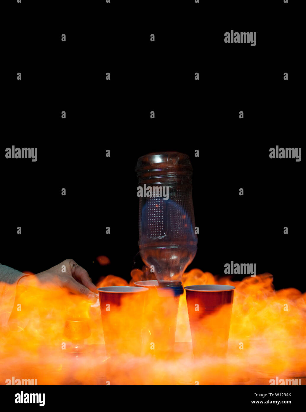 Hand lights an alcohol rocket, made out of a juice bottle. Explosion ...