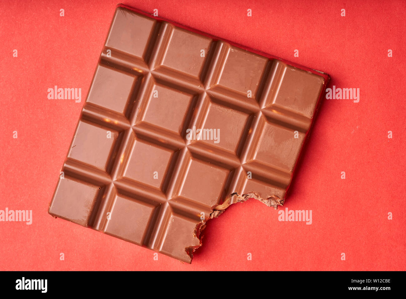 Bitten bar of milk chocolate on a colored paper background Stock Photo ...