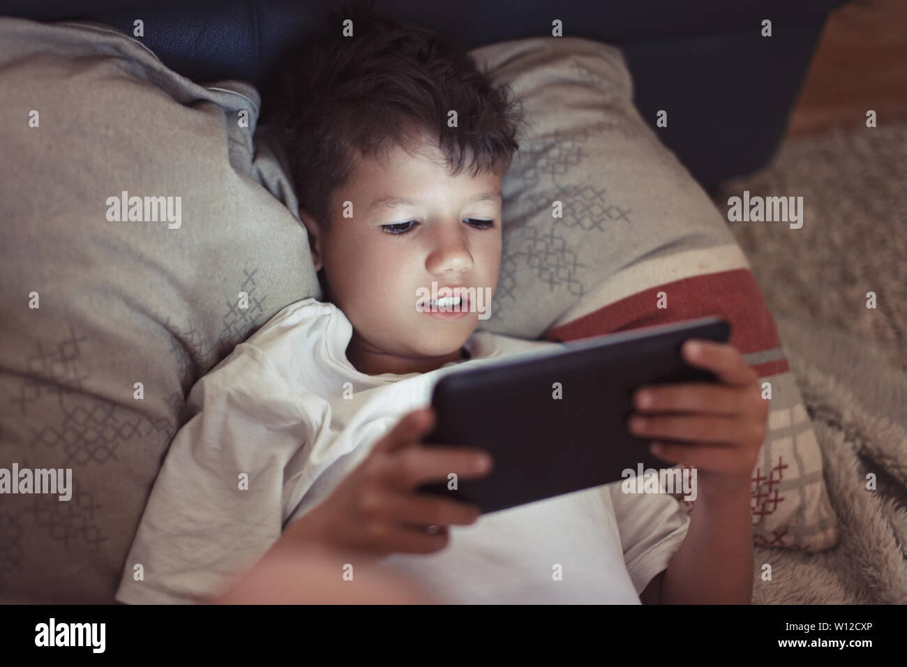 Little boy playing on digital tablet at night in dark bedroom Stock ...