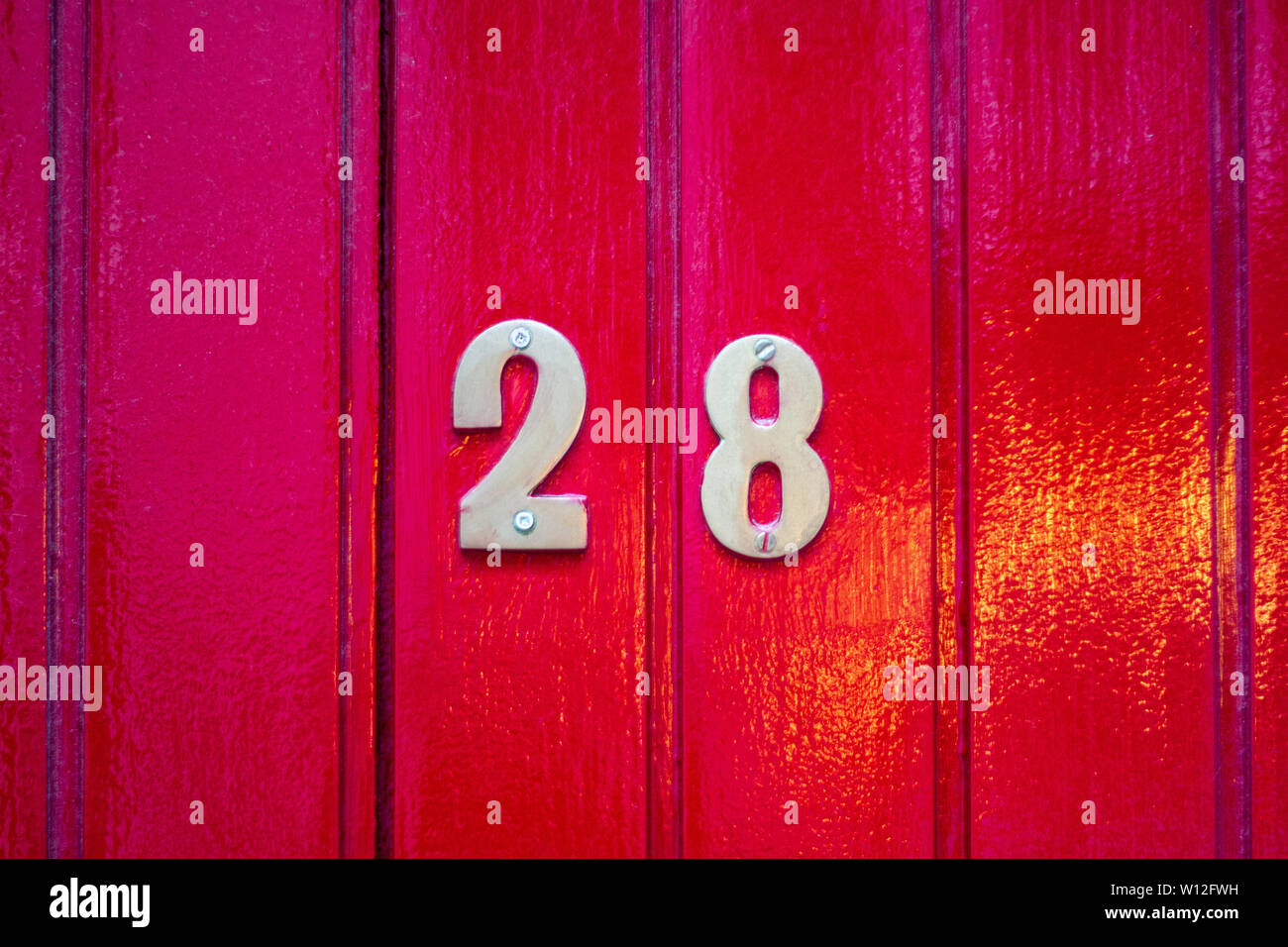 House number 28 on a bright red wooden front door made out of planks ...