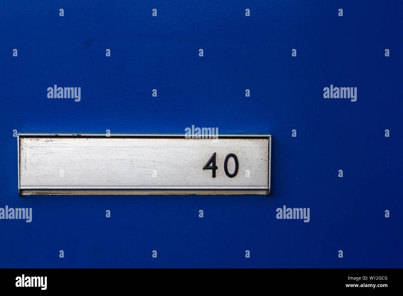 House number 40 with the forty in black on a silver letterbox on a blue ...