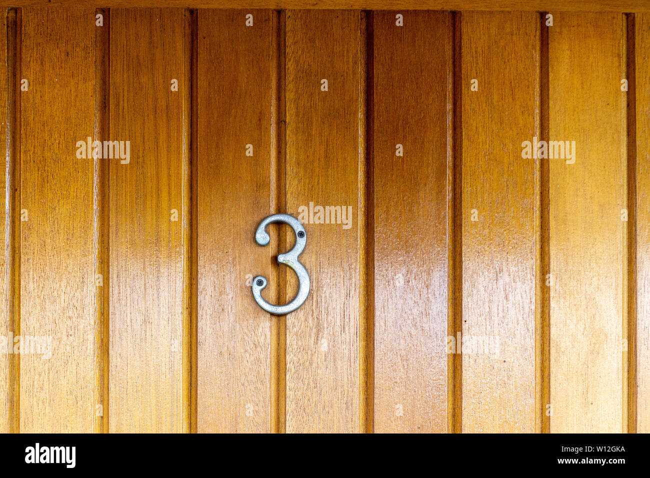 House number 3 with the three on a natural grained wooden door made out ...