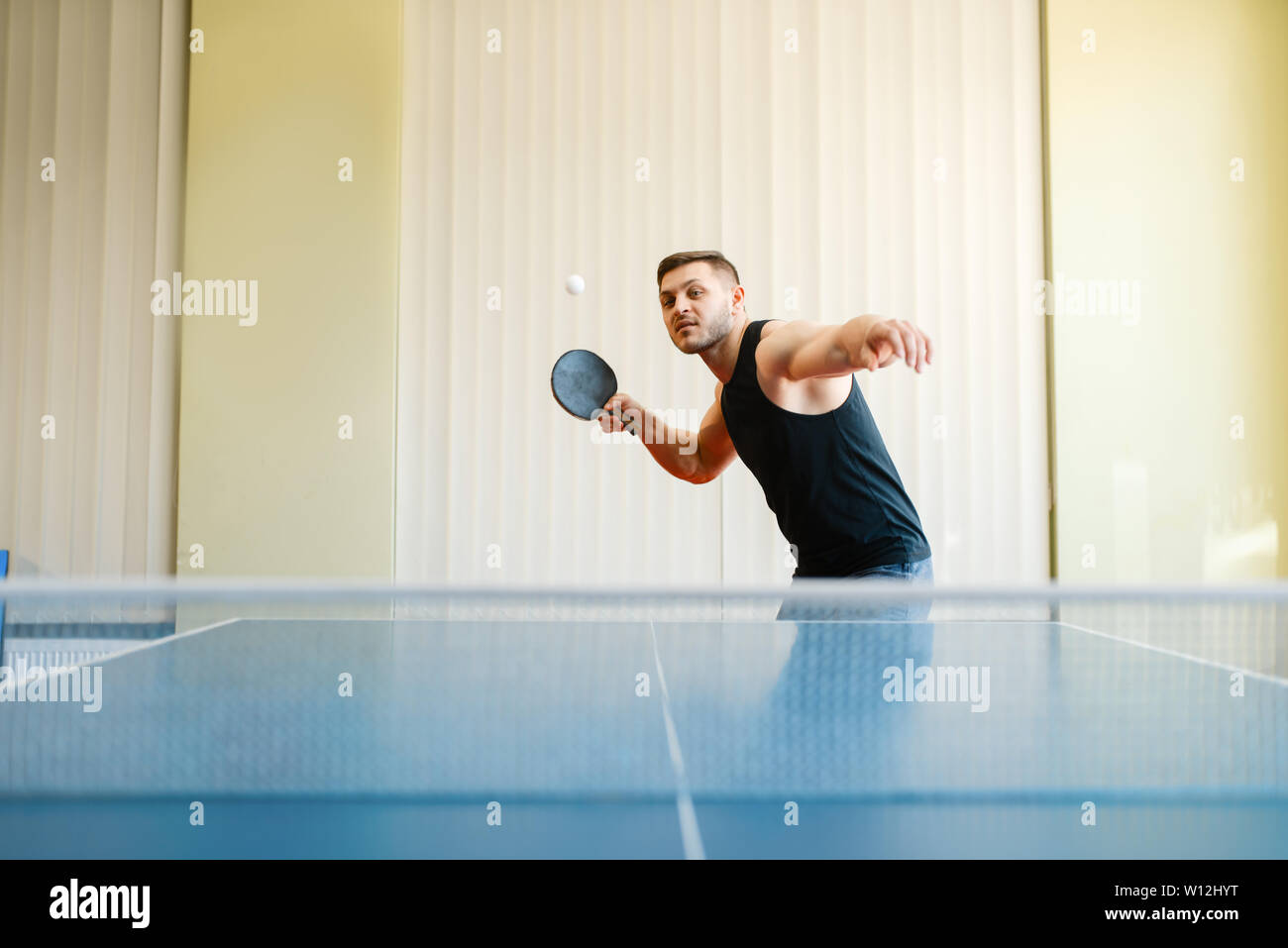 Man with racket and ball playing ping pong indoors Stock Photo - Alamy
