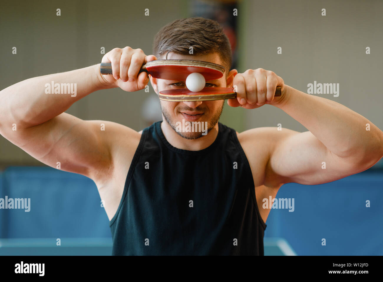 Man holds rackets and ping pong ball at his face Stock Photo - Alamy