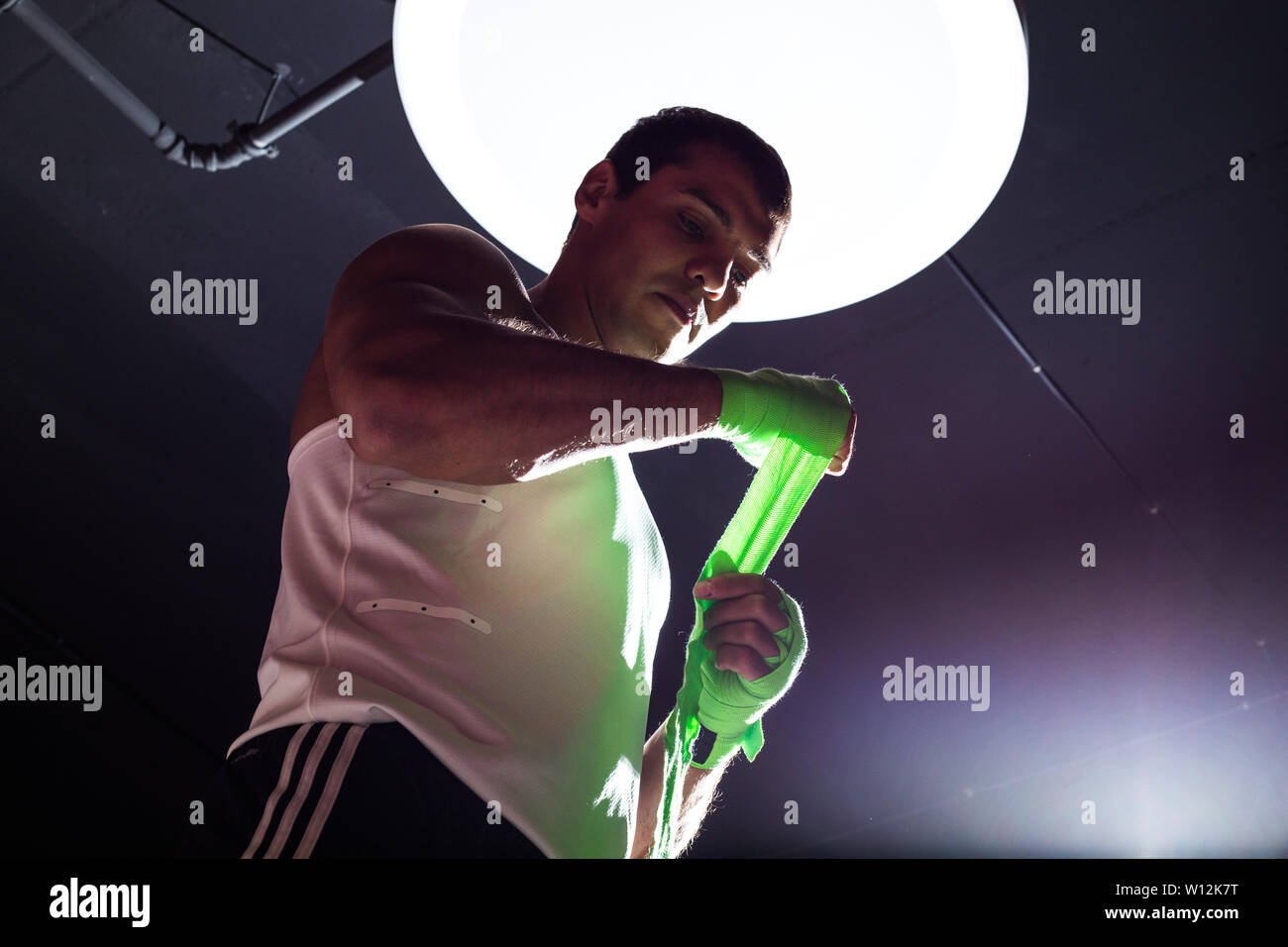 Sports man stands in the ring and reels boxing bandage. Male boxer ...